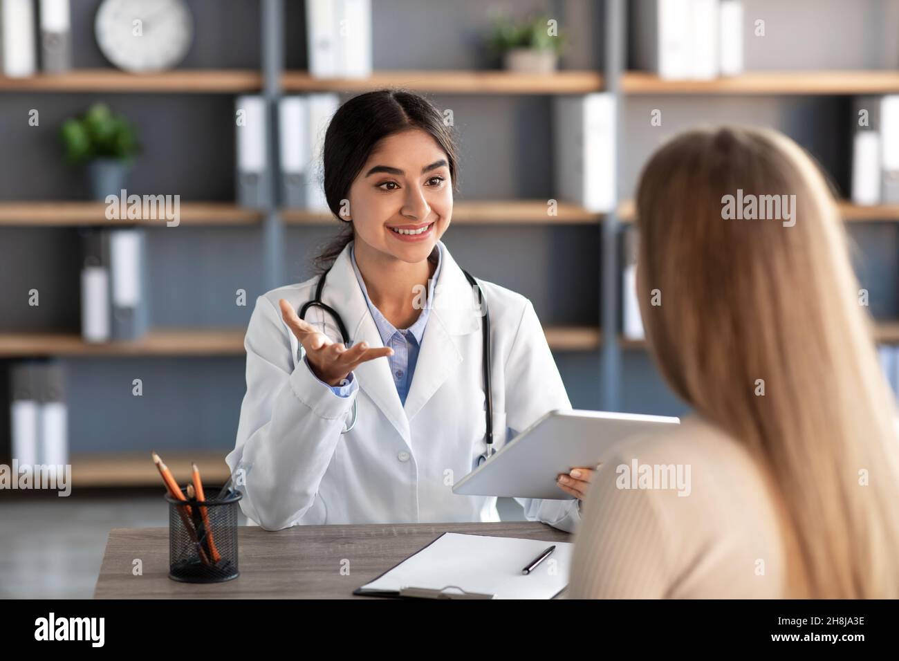 Smiling young attractive indian lady medical worker in white coat ...