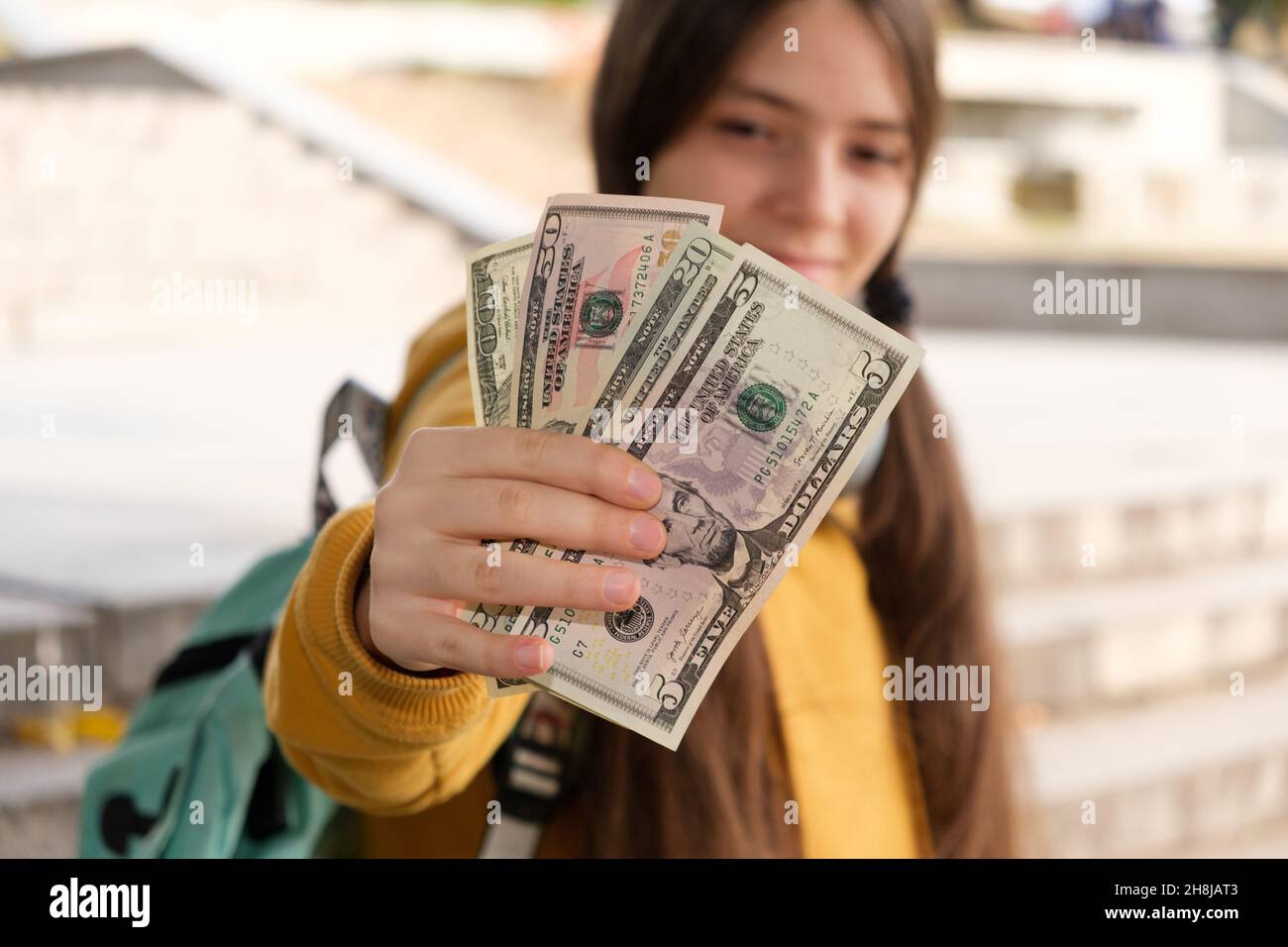 A teenage girl shows a lot of dollar bills and smiles Stock Photo - Alamy