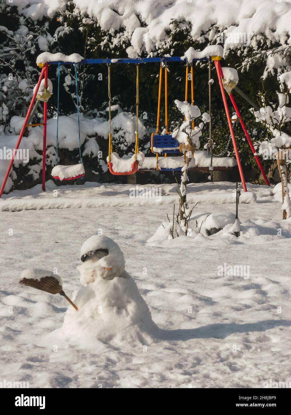Vertical shot of a snowman and swings in a snowy garden Stock Photo - Alamy
