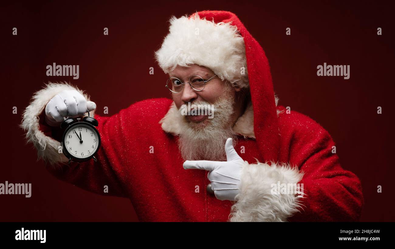 Santa claus pointing at alarm clock almost midnight Stock Photo - Alamy