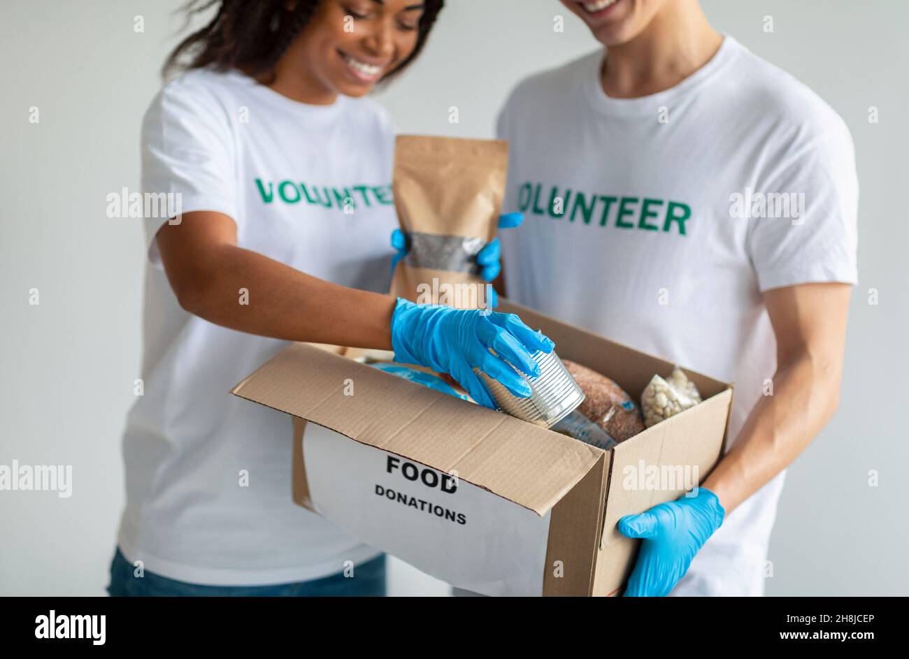Young diverse volunteer woman and man packing food donations in ...