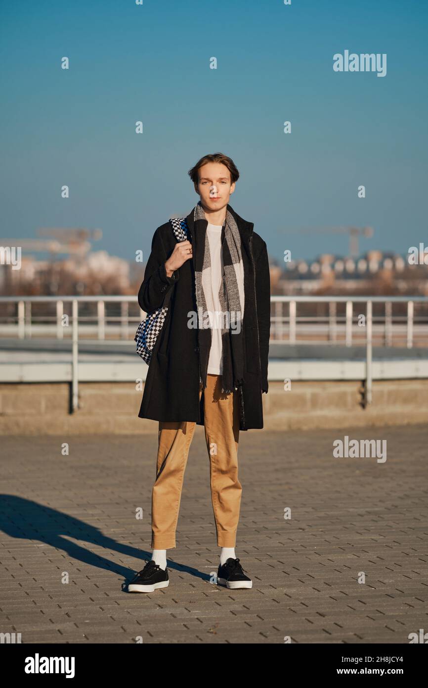 Full length portrait of young man in old wool coat, scarf and short ...