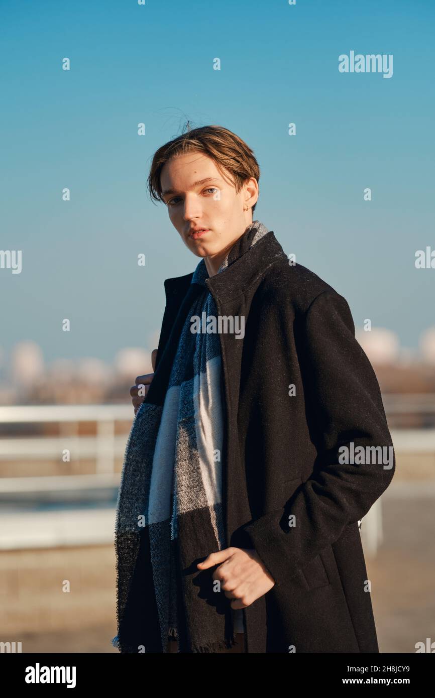 Young man in old wool coat, scarf and short trousers outdoor with hand ...