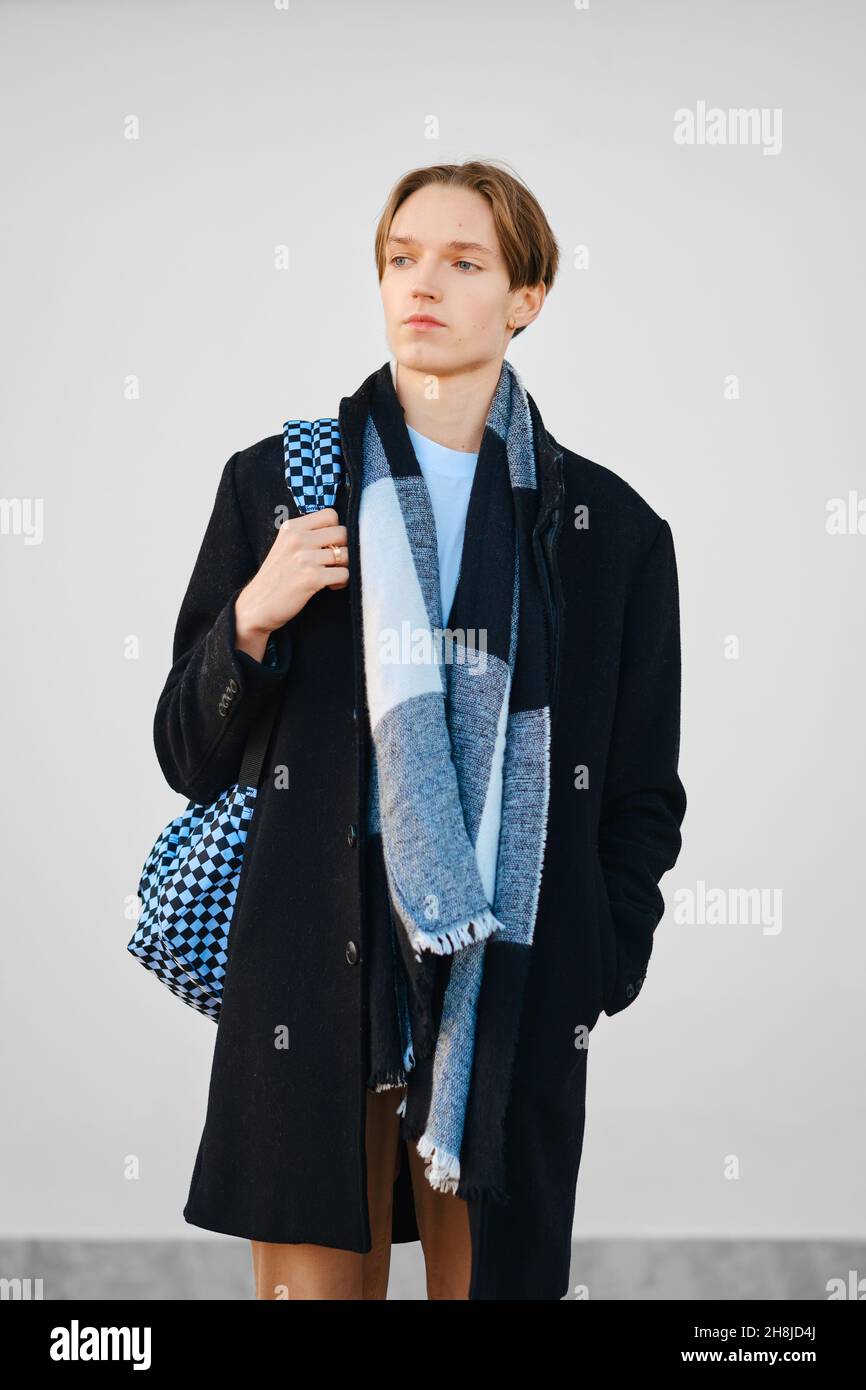 Young student with backpack in old wool coat, scarf and looking away to ...