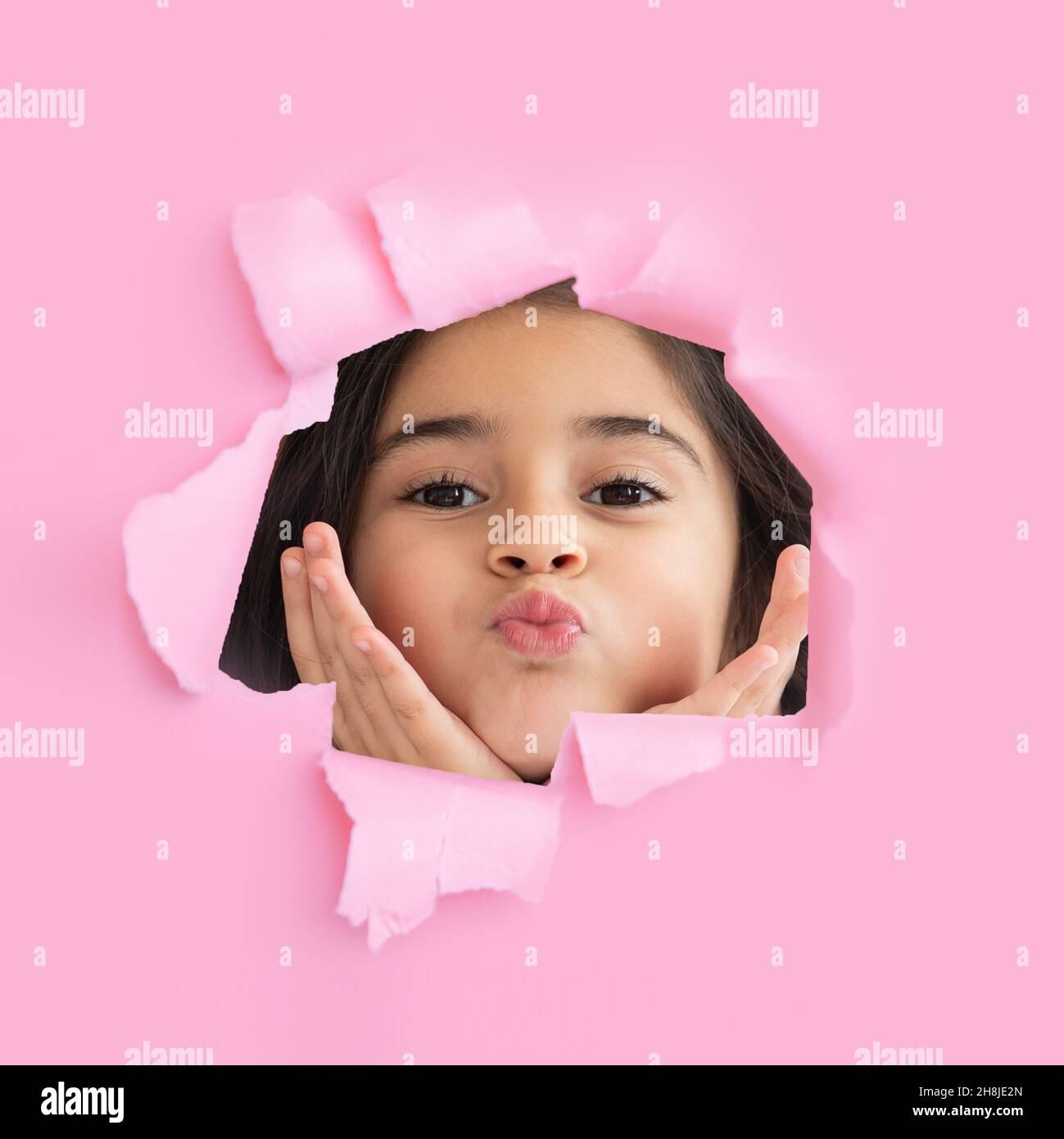 Cheerful cute arabic little girl have fun, blowing lips and looks into ...
