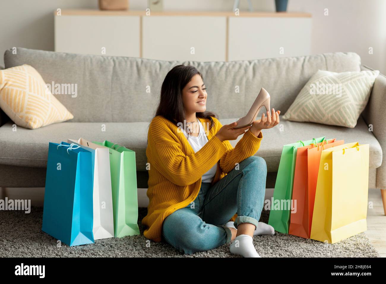 Remote shopping concept. Excited arab lady holding new shoe, sitting ...