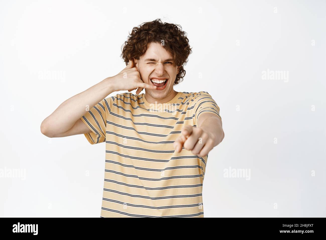 Sassy curly guy shows mobile phone gesture, pointing finger at you to ...