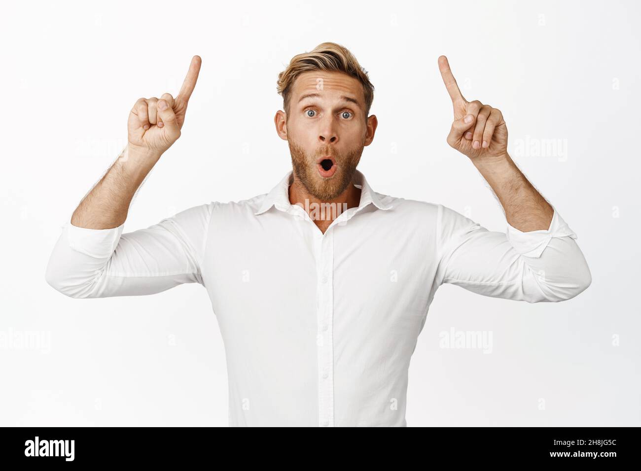 Excited blond man say wow, pointing fingers up, showing advertisement ...