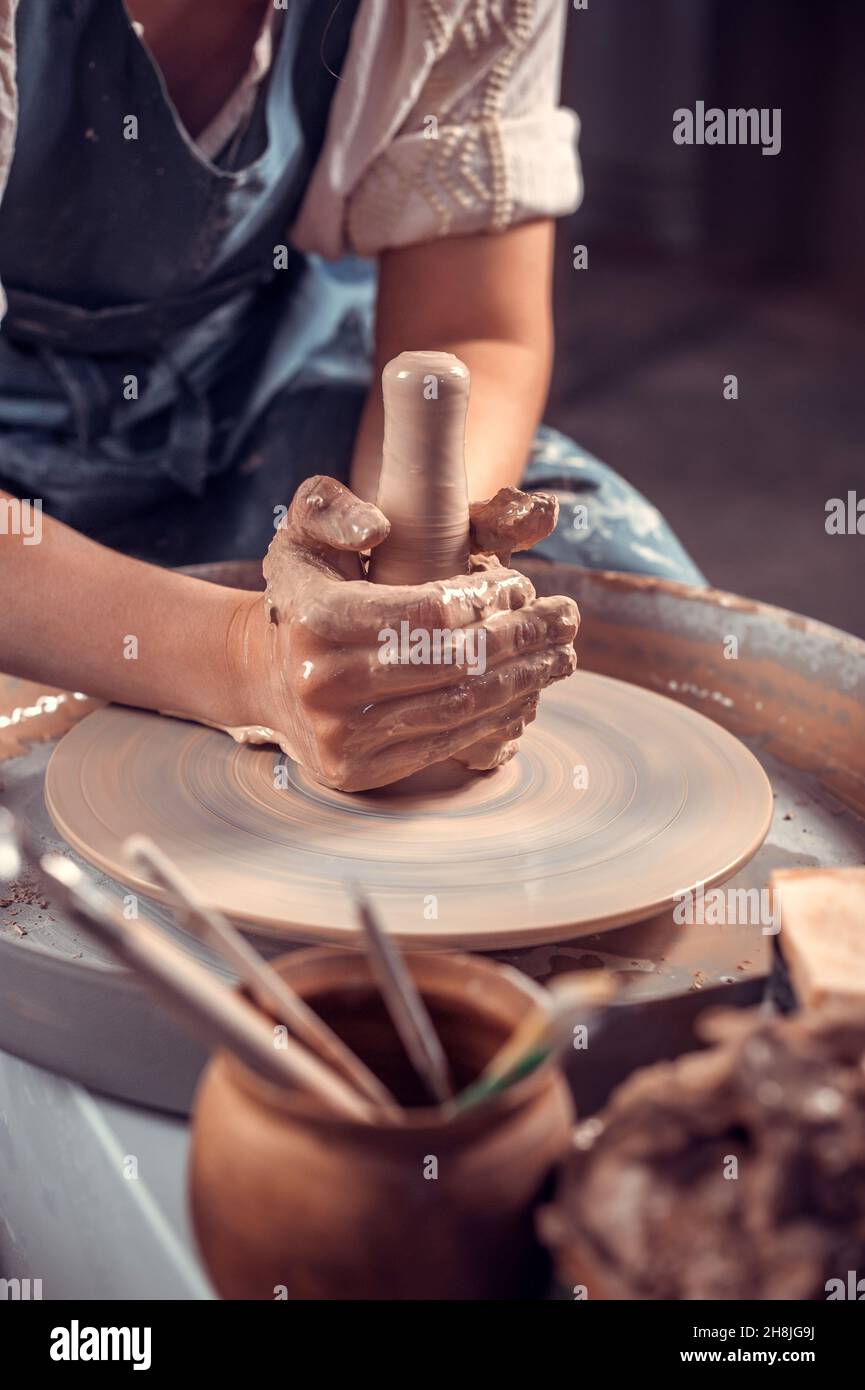 The potter works in the workshop. Hands and a potter's wheel close-up ...