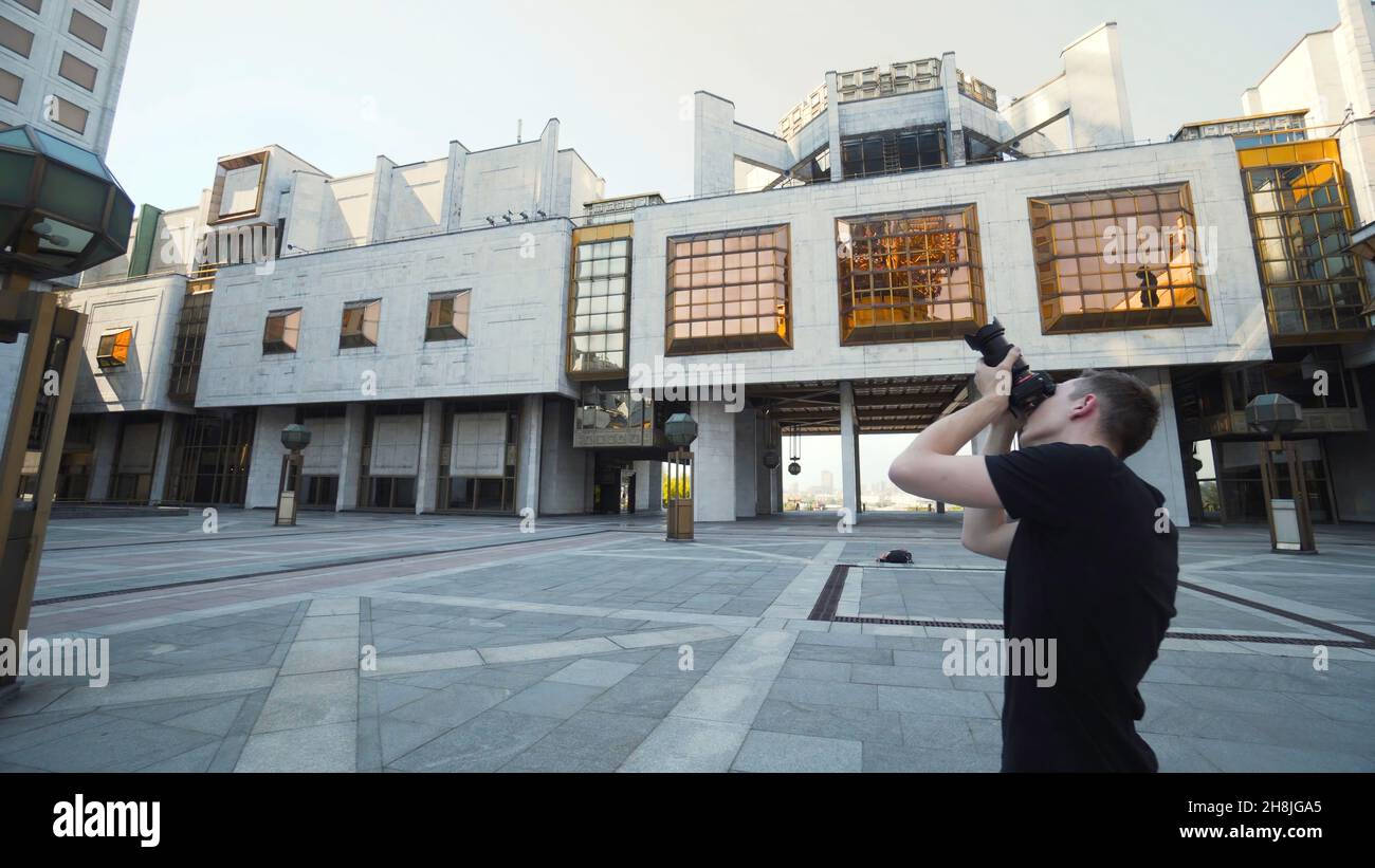 Young man photographs popular buildings in city. Action. Guy takes ...