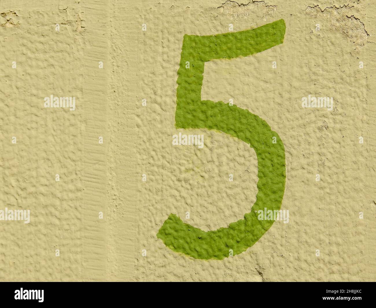 Close-up shot of a big green number 5 painted on an old weathered ...
