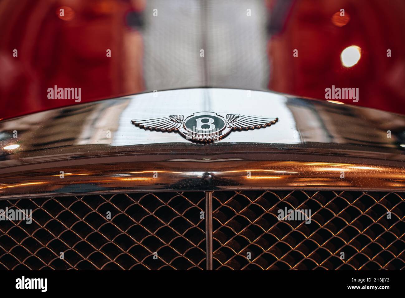 Silver famous Bentley Logo on the front of red Bentley Continental car ...