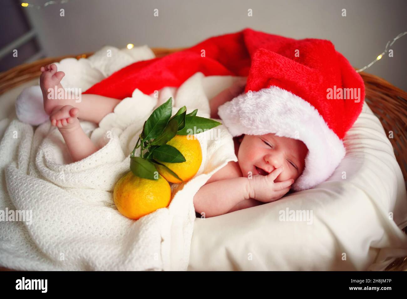 Caucasian newborn baby in Santa's Christmas cap lies in a basket with ...