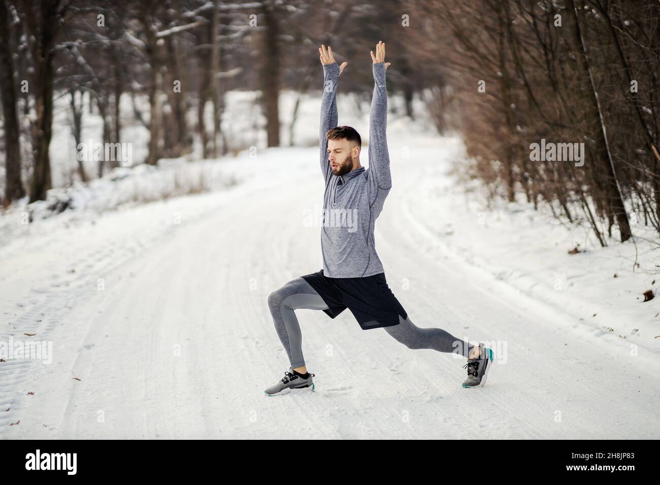 Fit sportsman doing warm up exercises in nature on snow at winter ...