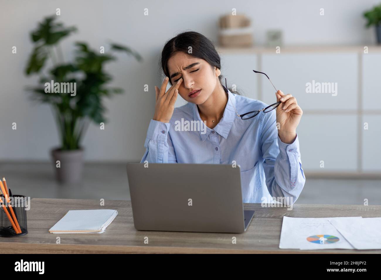 Sad millennial indian female employee suffer from headache, fatigue ...
