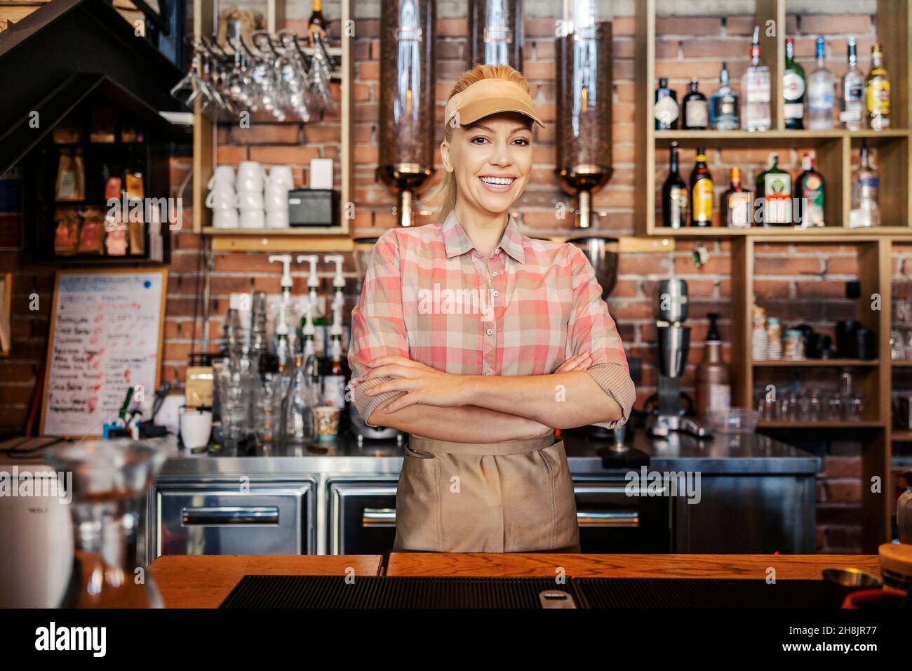 Waitress at the bar. The blonde stands in a cafe and wears a plaid ...