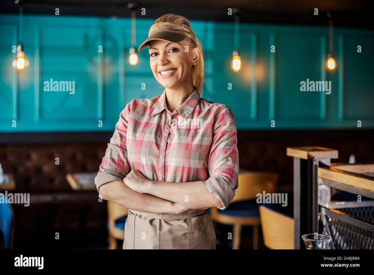 Waitress at the restaurant. The blonde server wears a plaid shirt, cap ...