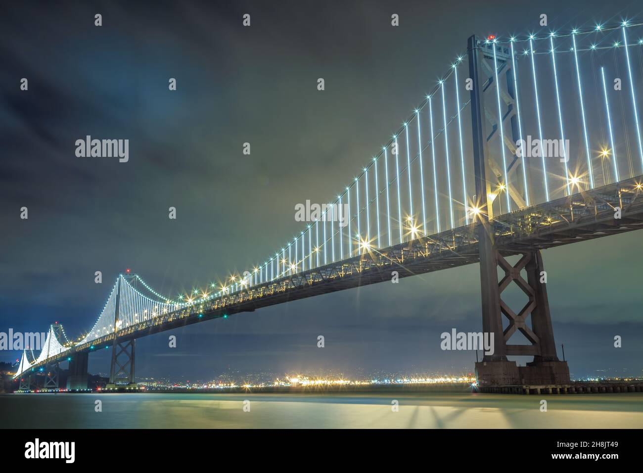 A nighttime photograph captures the iconic Bay Bridge in San Francisco ...
