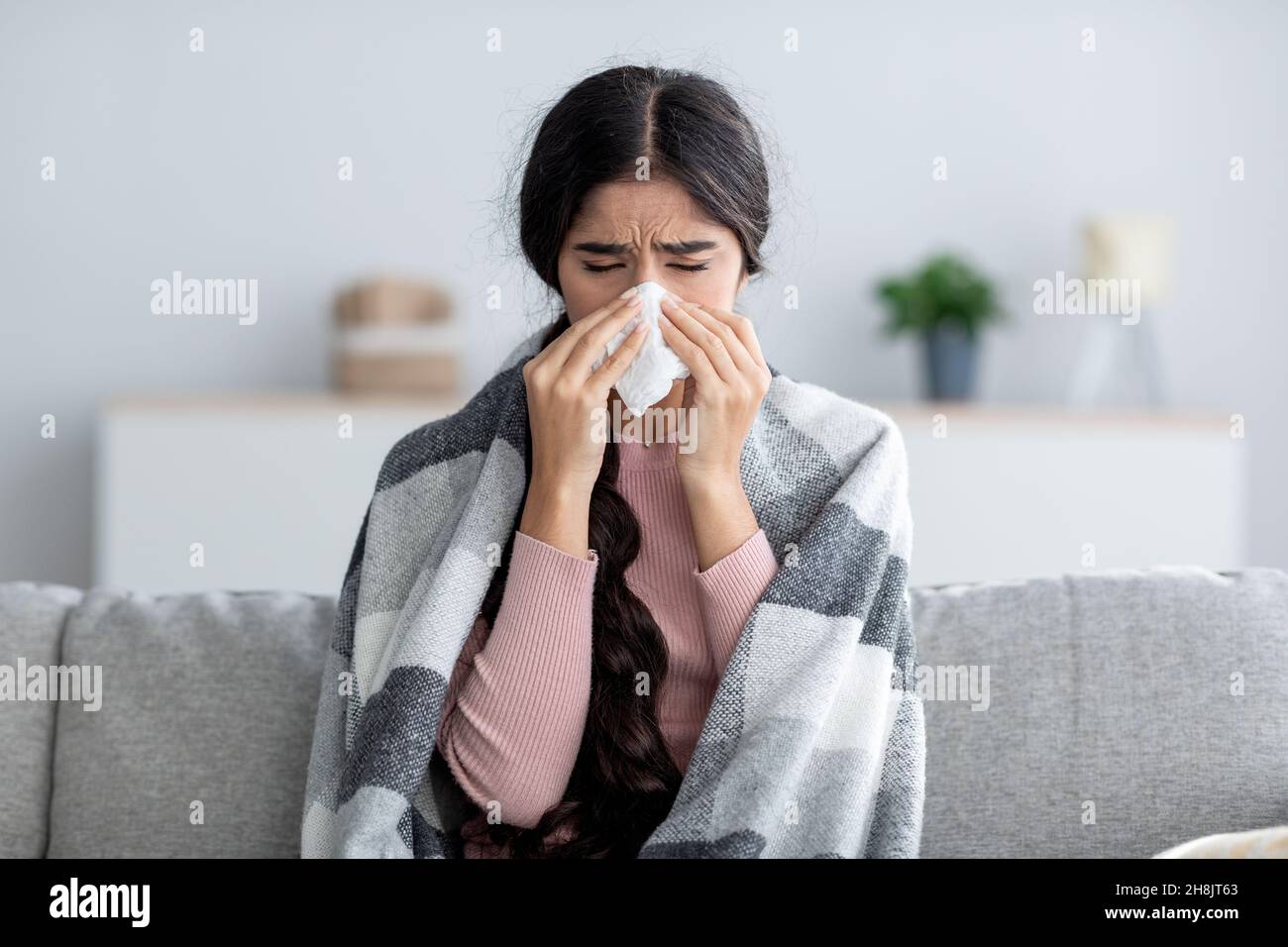 Unhappy sad young indian female in plaid suffering from fever and flu ...