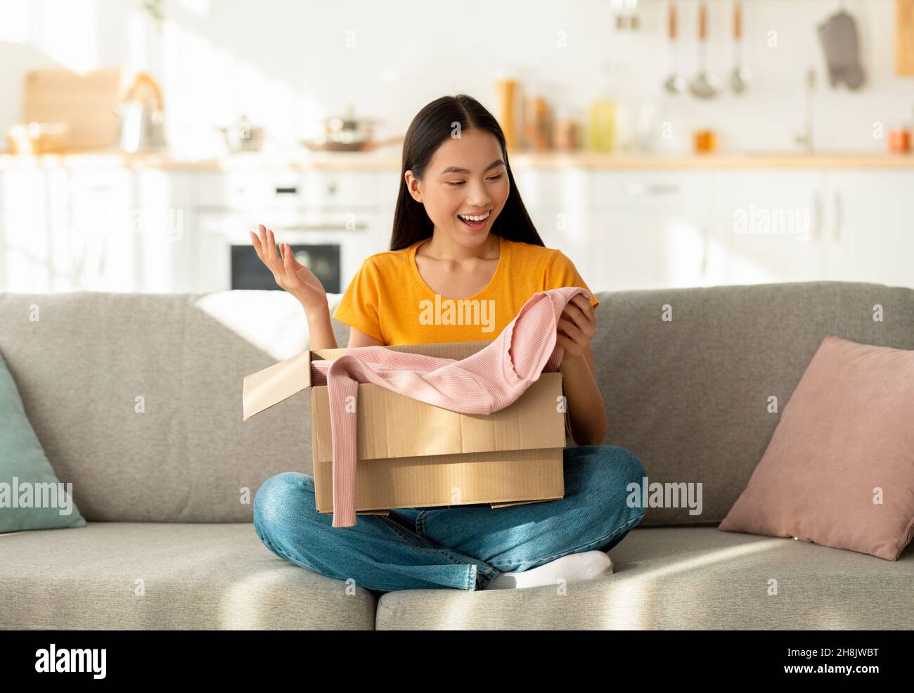 Ordering clothes online. Happy korean female customer opening parcel ...