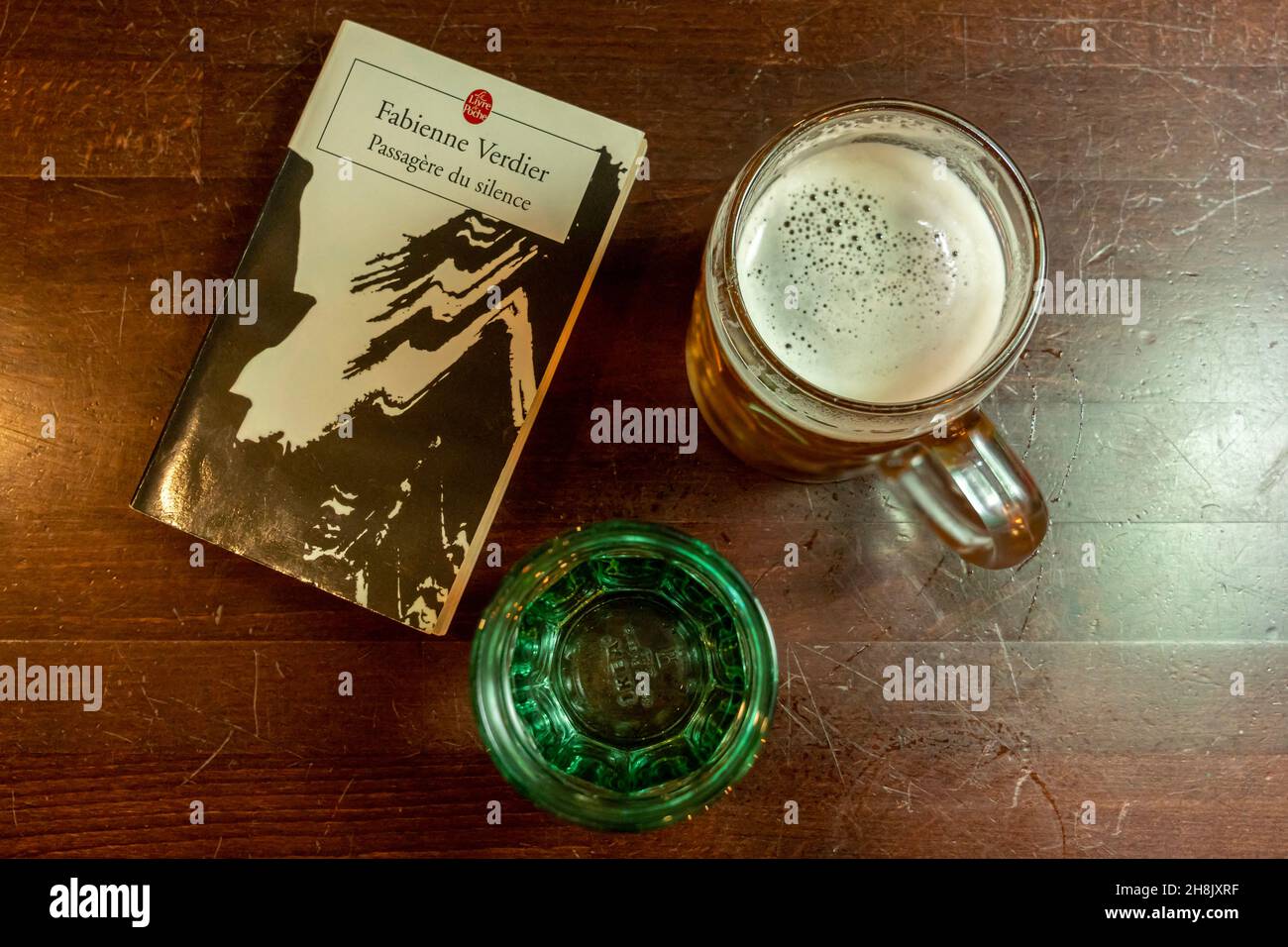 Paris, France - 11 27 2021: A woman reading a book and drinking a beer ...