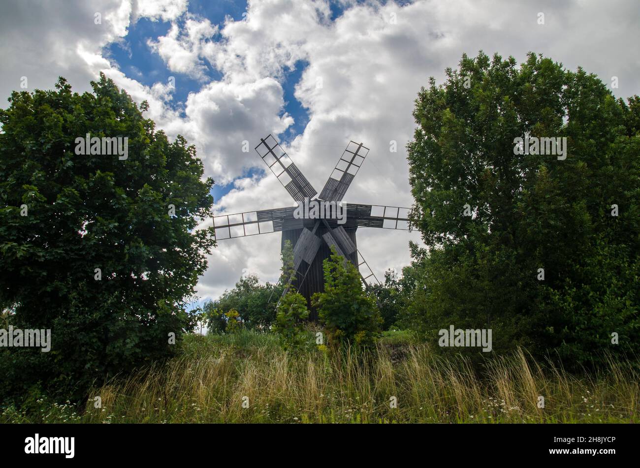 Gorgeous windmill among the trees, huge ancient windmill under summer ...
