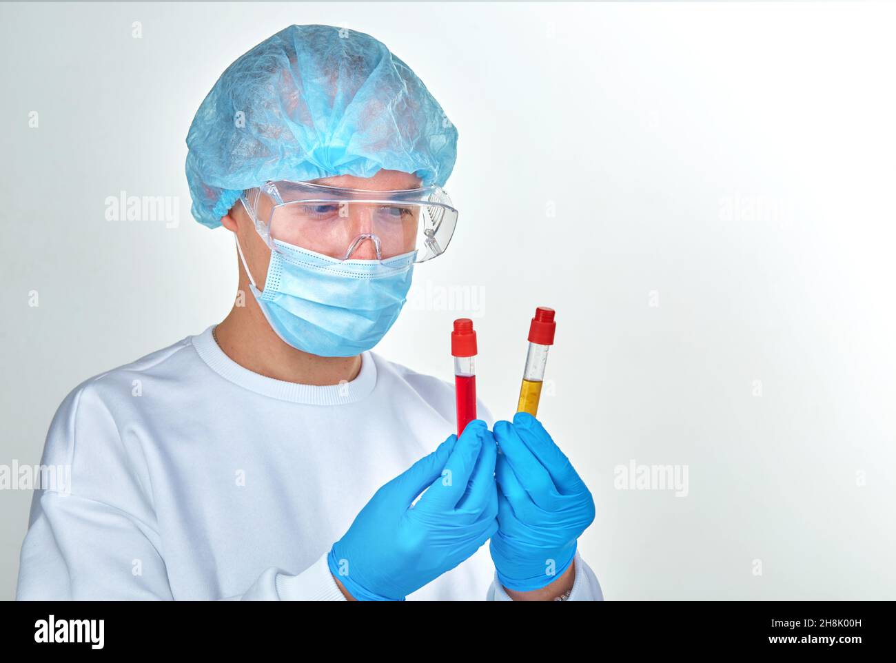 Doctor in mask looking at the blood test tube for coronavirus COVID19 ...