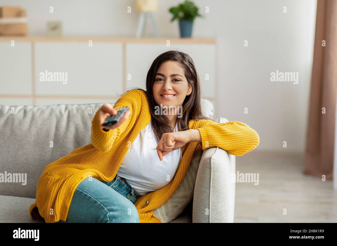 Excited arab woman switching TV channels with remote control, watching ...