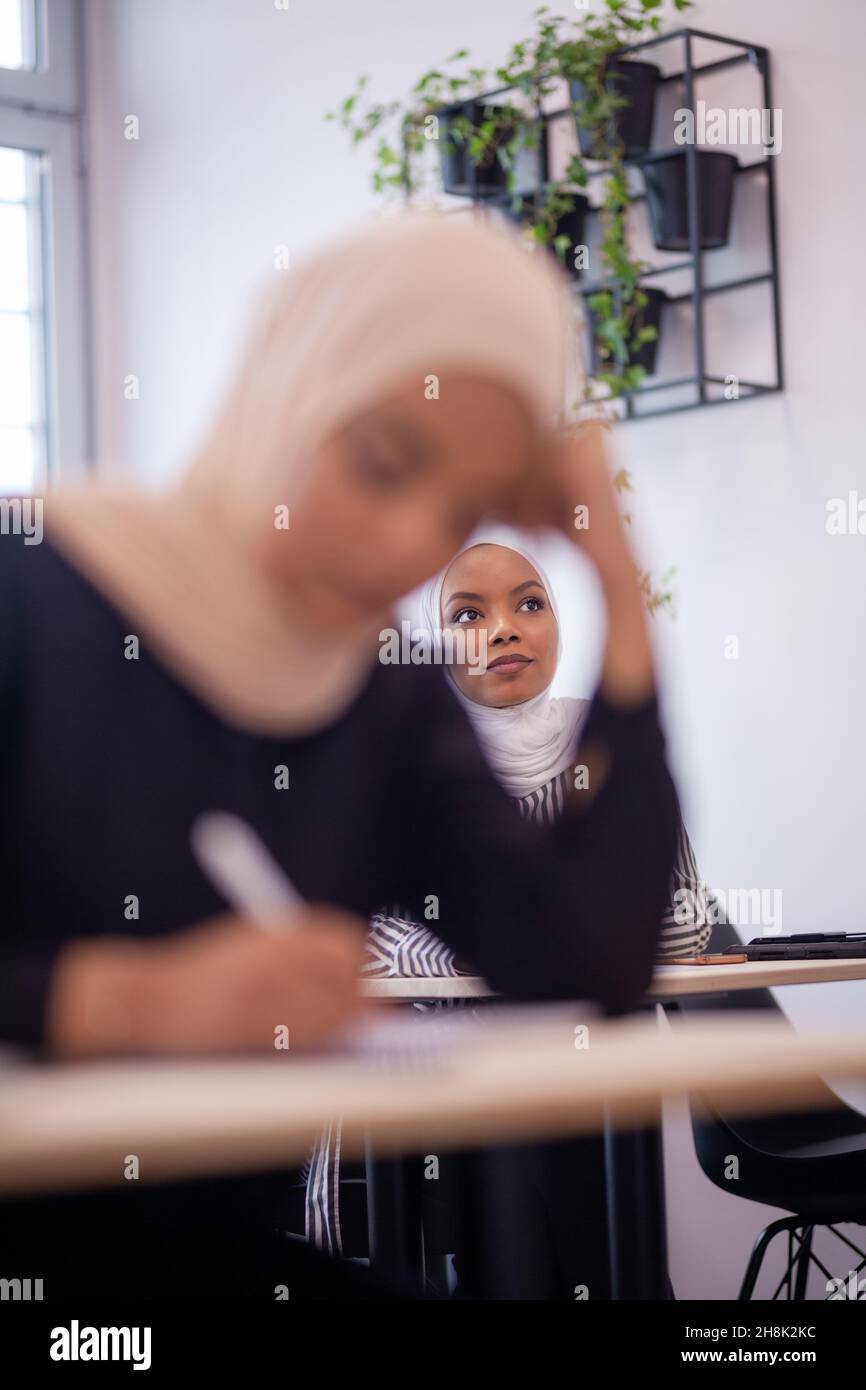 Students taking a test in a classroom. Smart young muslim girls with ...