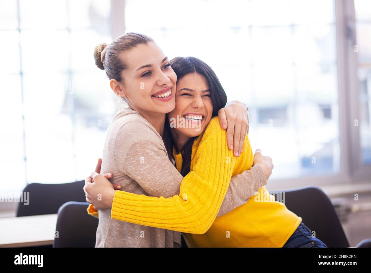 Beautiful female students in a classroom. Smart young girls hugging ...