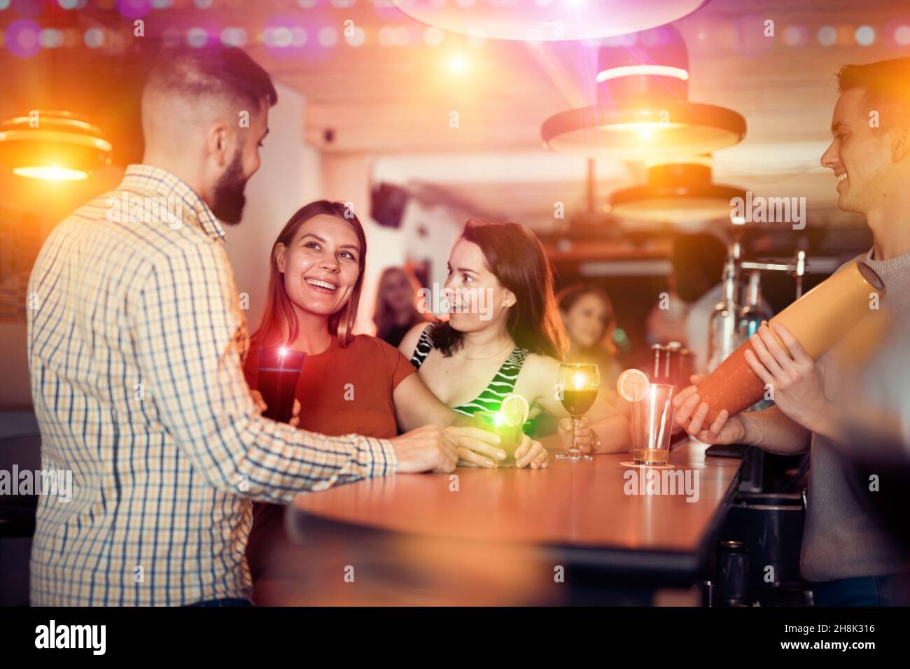Happy people and bartender shaking cocktail mixer Stock Photo - Alamy