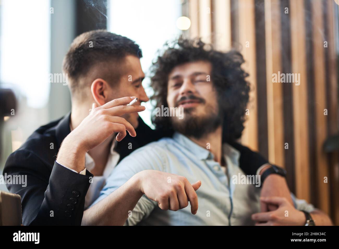 Two friends hugging in a cafe, having a cigarette Stock Photo - Alamy