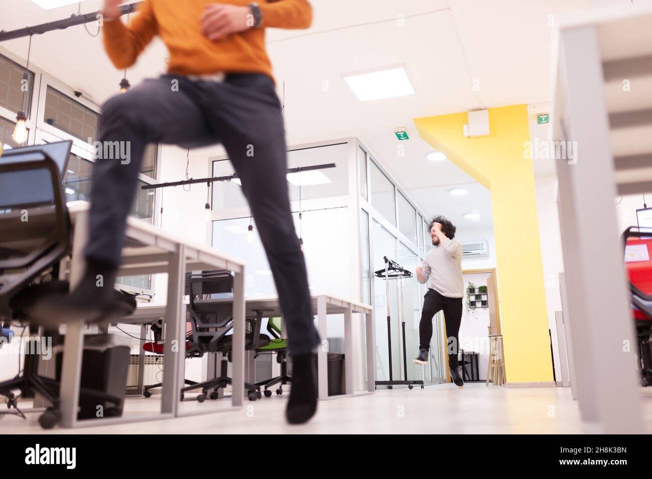 Two businessmen having fun at the office. Friendly colleagues jumping ...