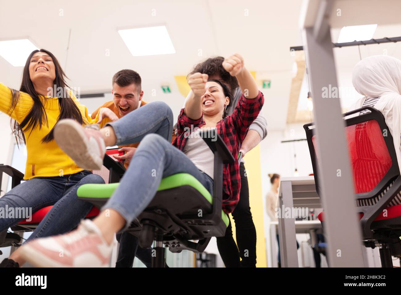 Colleagues having fun on work at the office. Girls pushing boys on ...