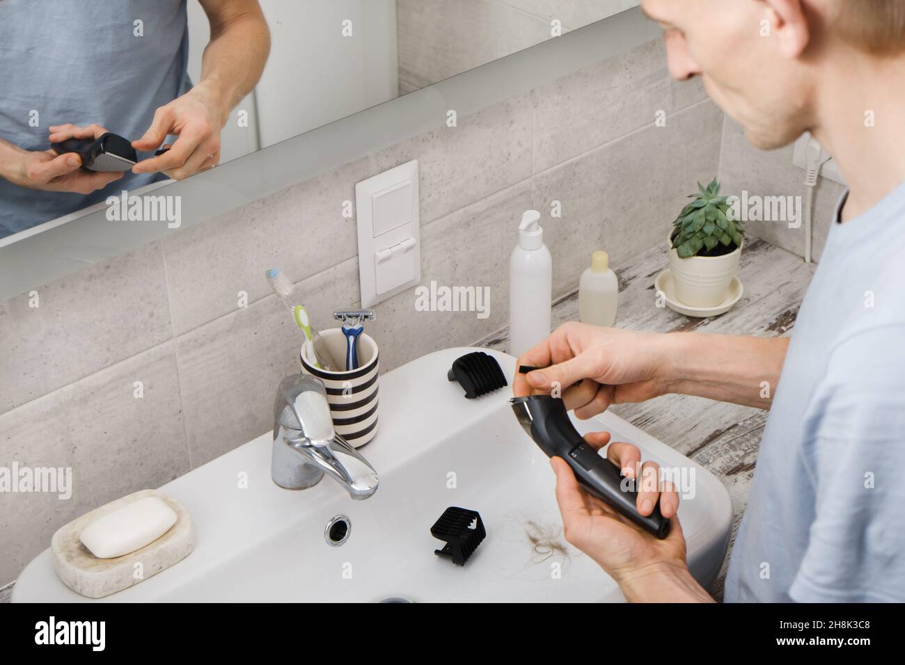 Man cleaning electronic shaving razor in sink, male self care and ...