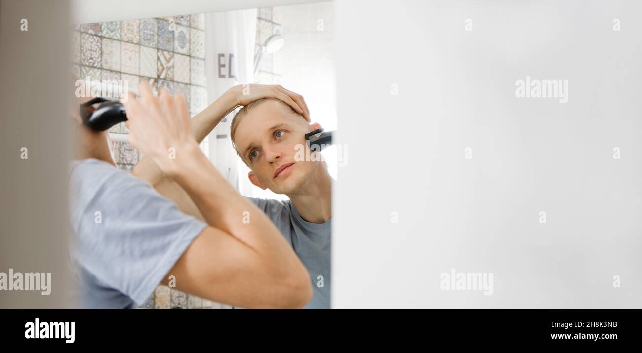 Man shaving whiskers hair by himself, self haircut at home in front of ...