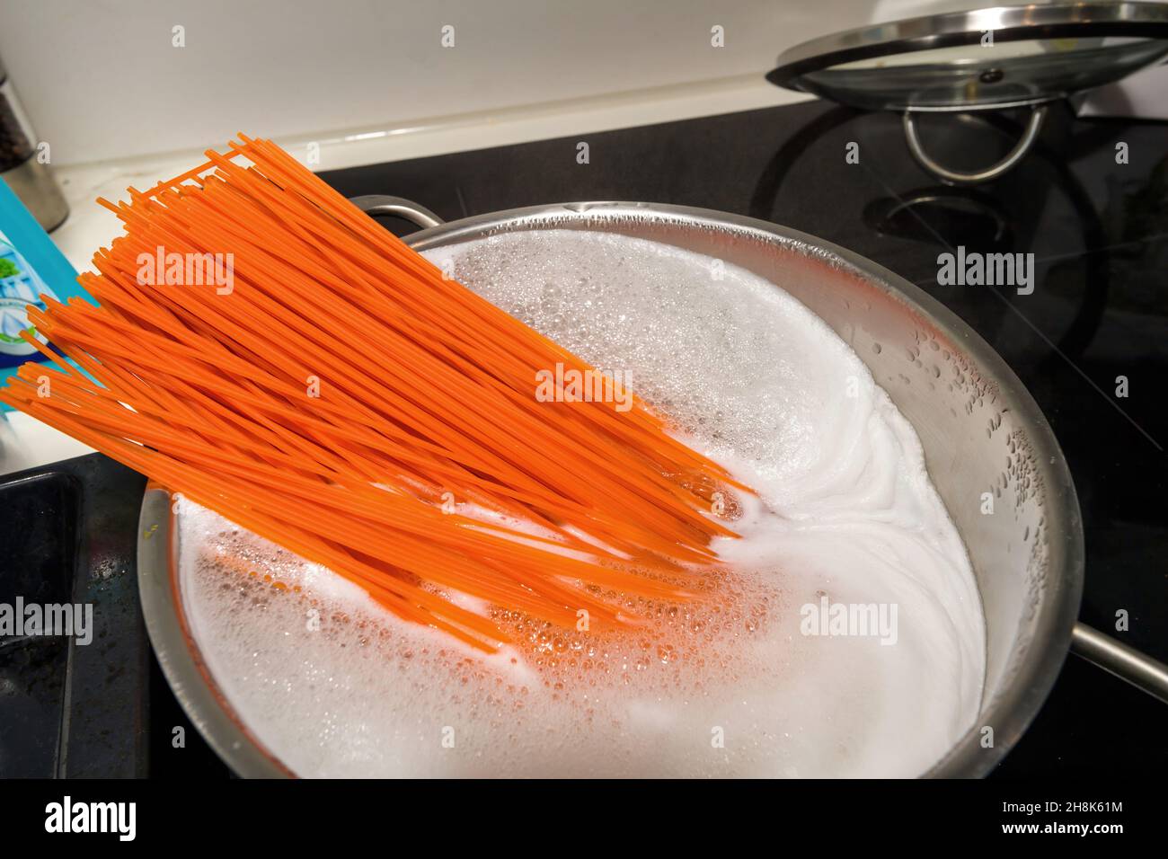 arge pot boiling red orange pasta on induction table Stock Photo - Alamy