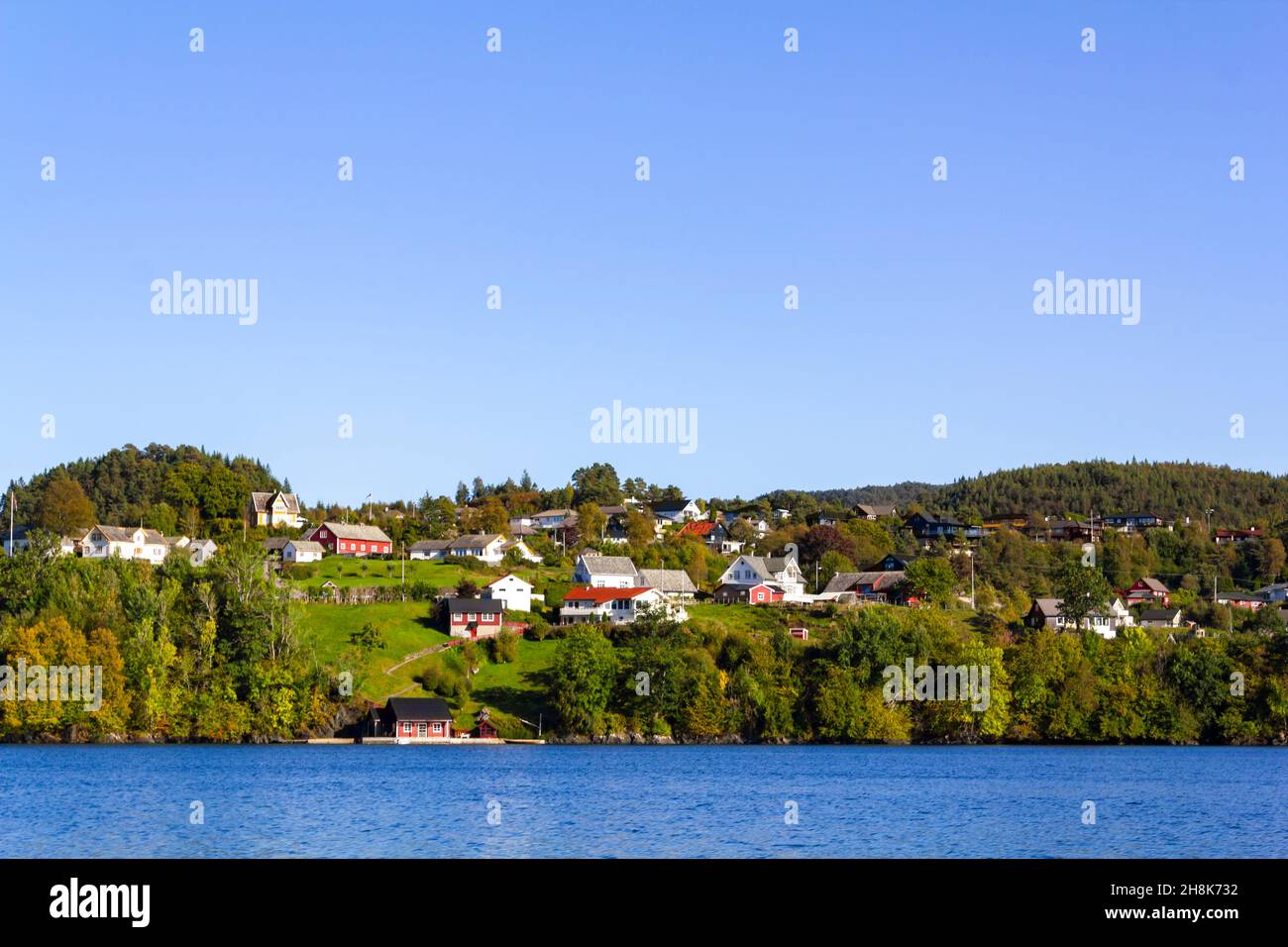 Colorful traditional Norwegian houses near the sea with green forest on ...