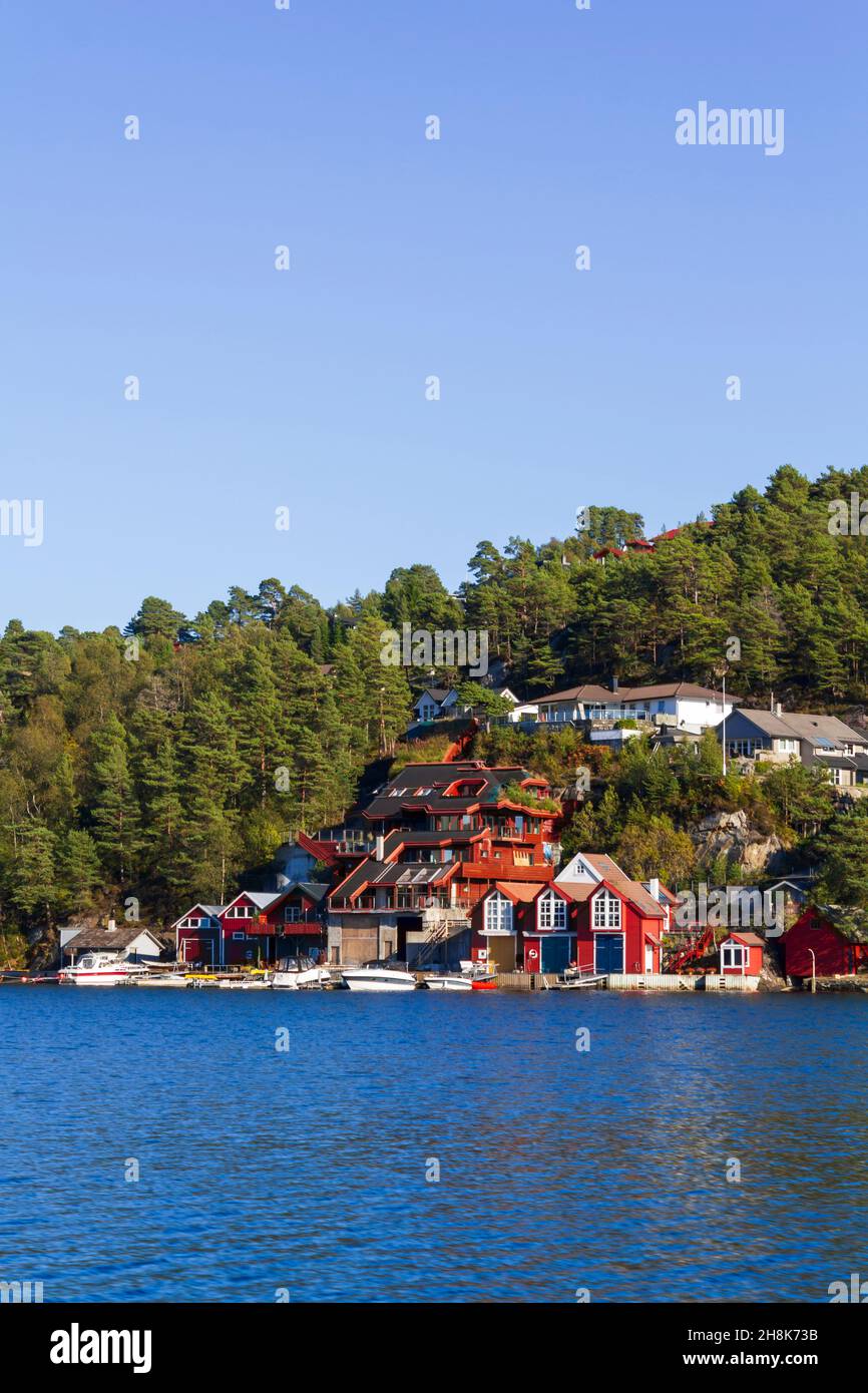 Colorful traditional Norwegian houses near the sea with green forest on ...