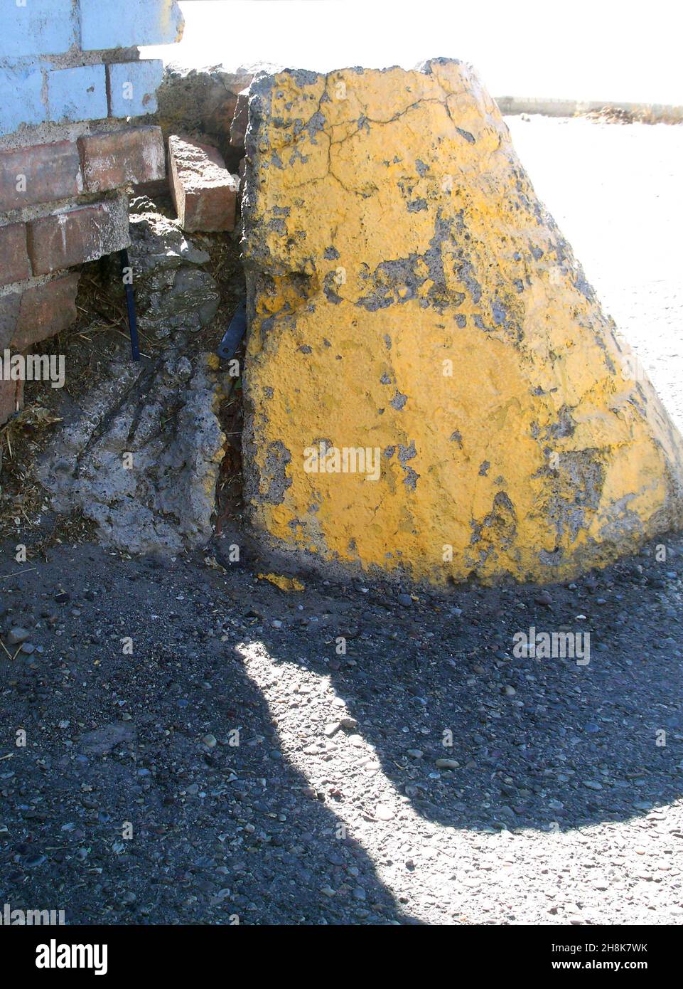 Crumbling yellow roadside cement blocker to keep cars from bumping into ...
