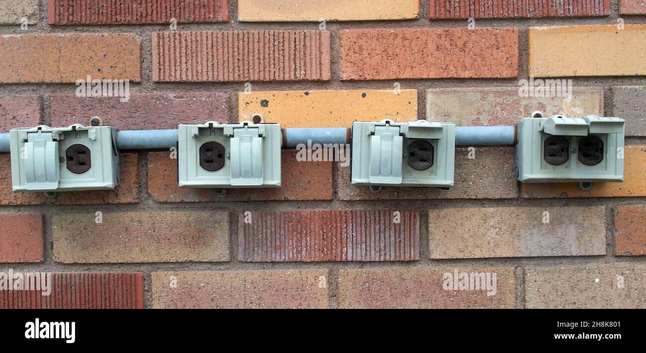 4 outdoor outlets hanging on the side of a multi colored brick wall ...