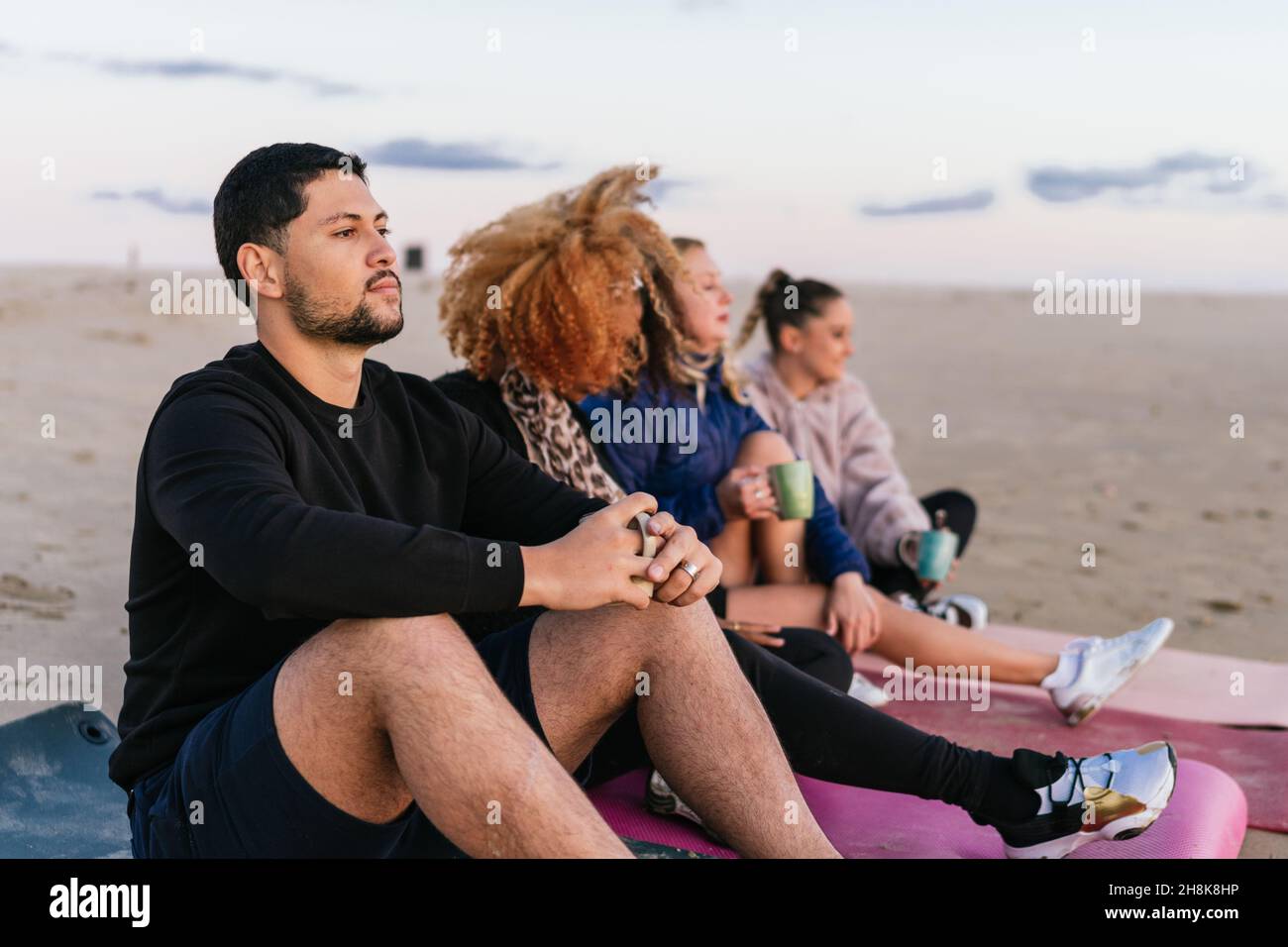 People sitting on mats on the beach drinking tea during the sunset ...