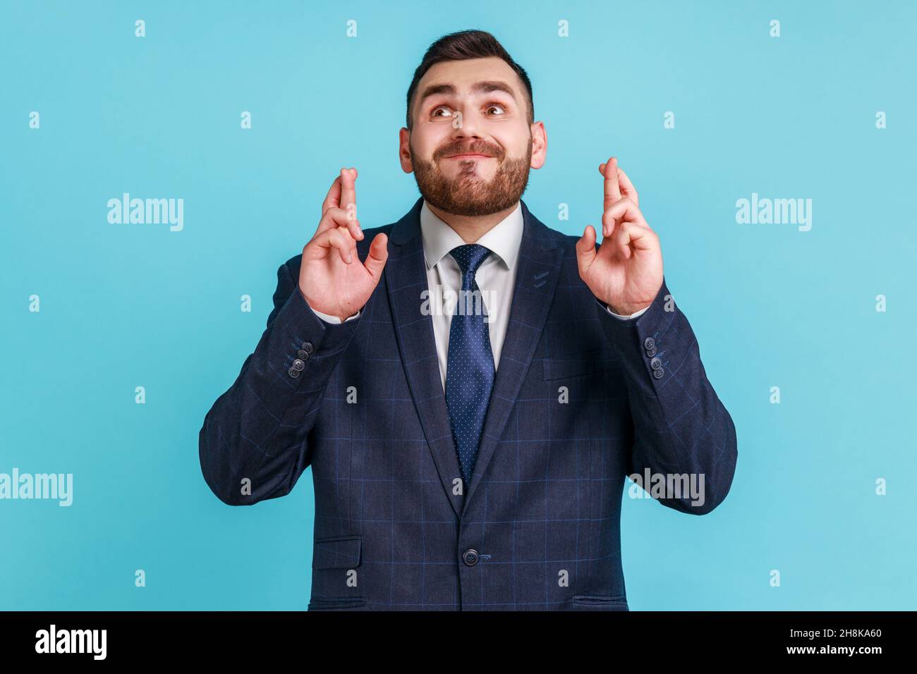 Portrait of hopeful man with beard wearing official style suit crossing ...
