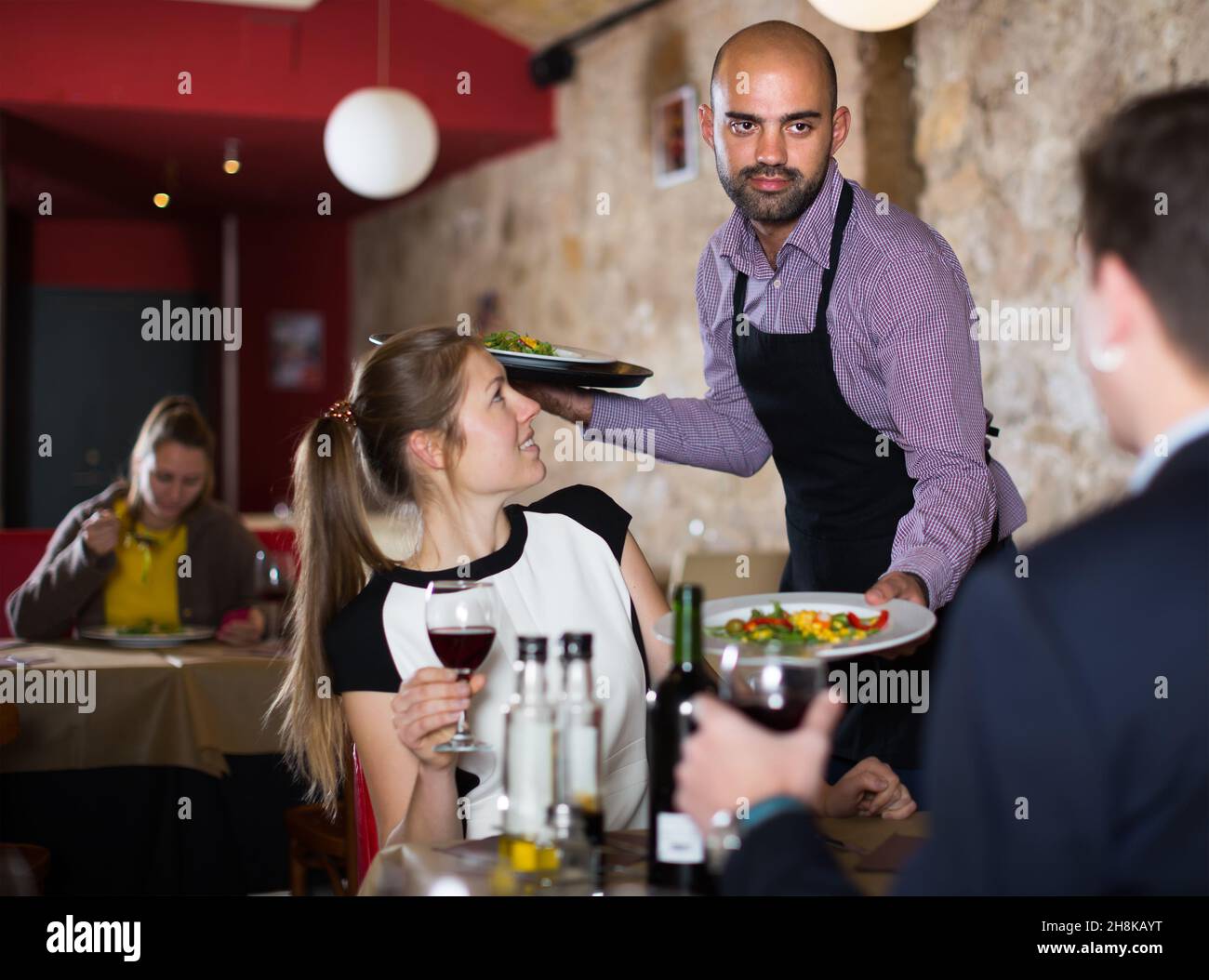 Friendly guy waiter serving meals to young couple Stock Photo - Alamy