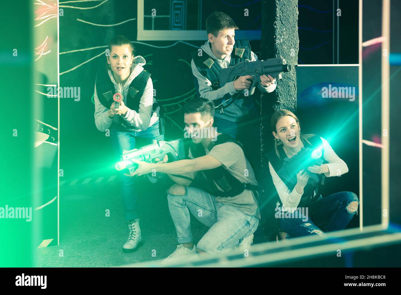 Smiling young friends playing laser tag game with colored laser Stock ...