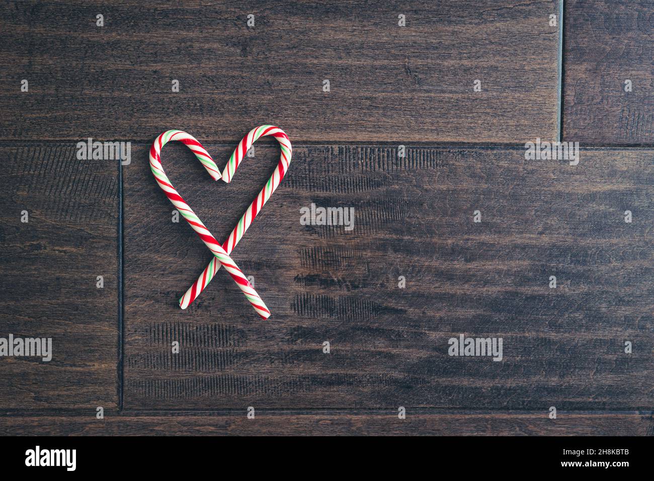Simple candy cane heart isolated on a dark wood background with copy ...