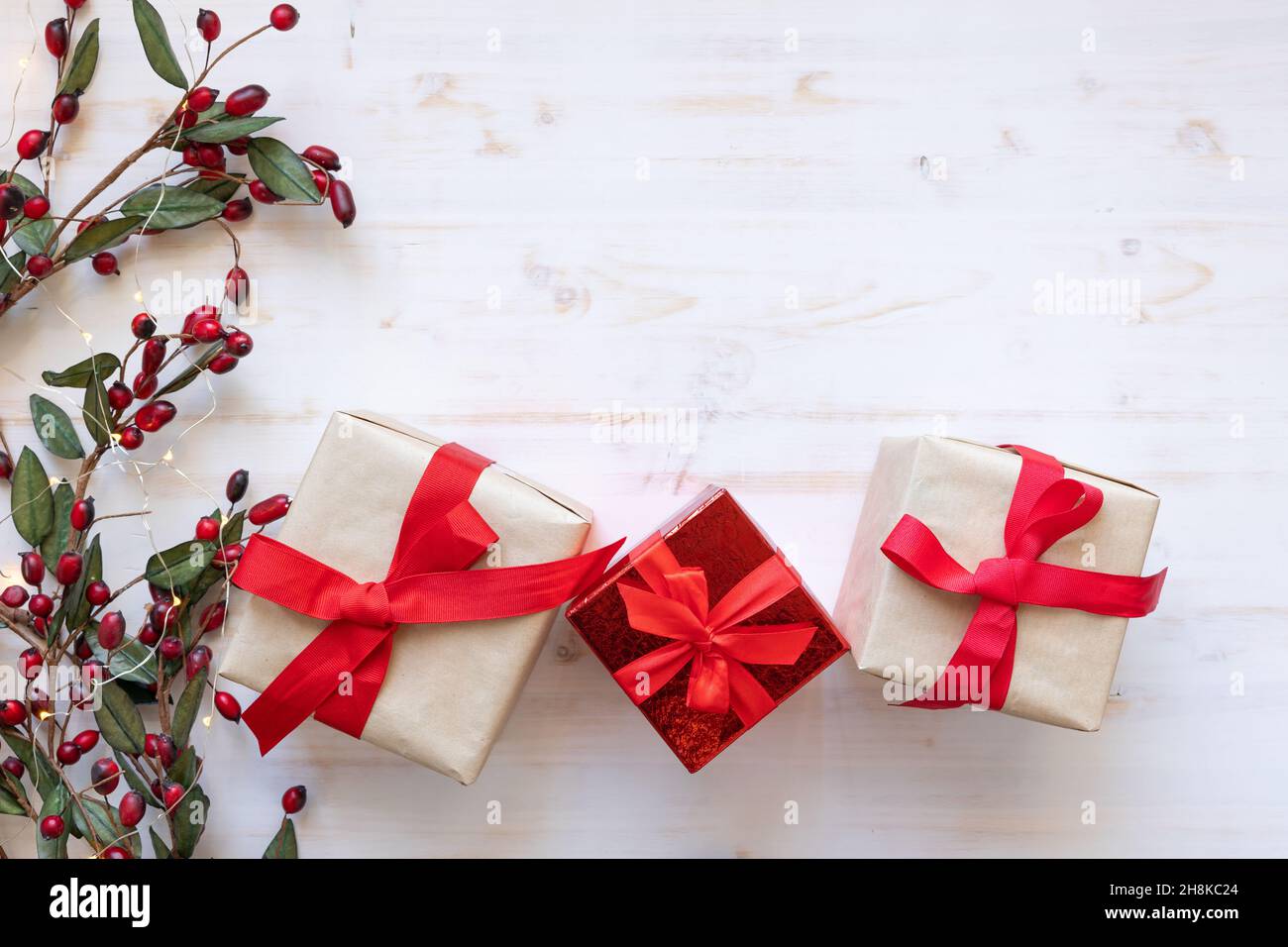 Three Christmas gifts with red ribbon bows on a white wood background ...