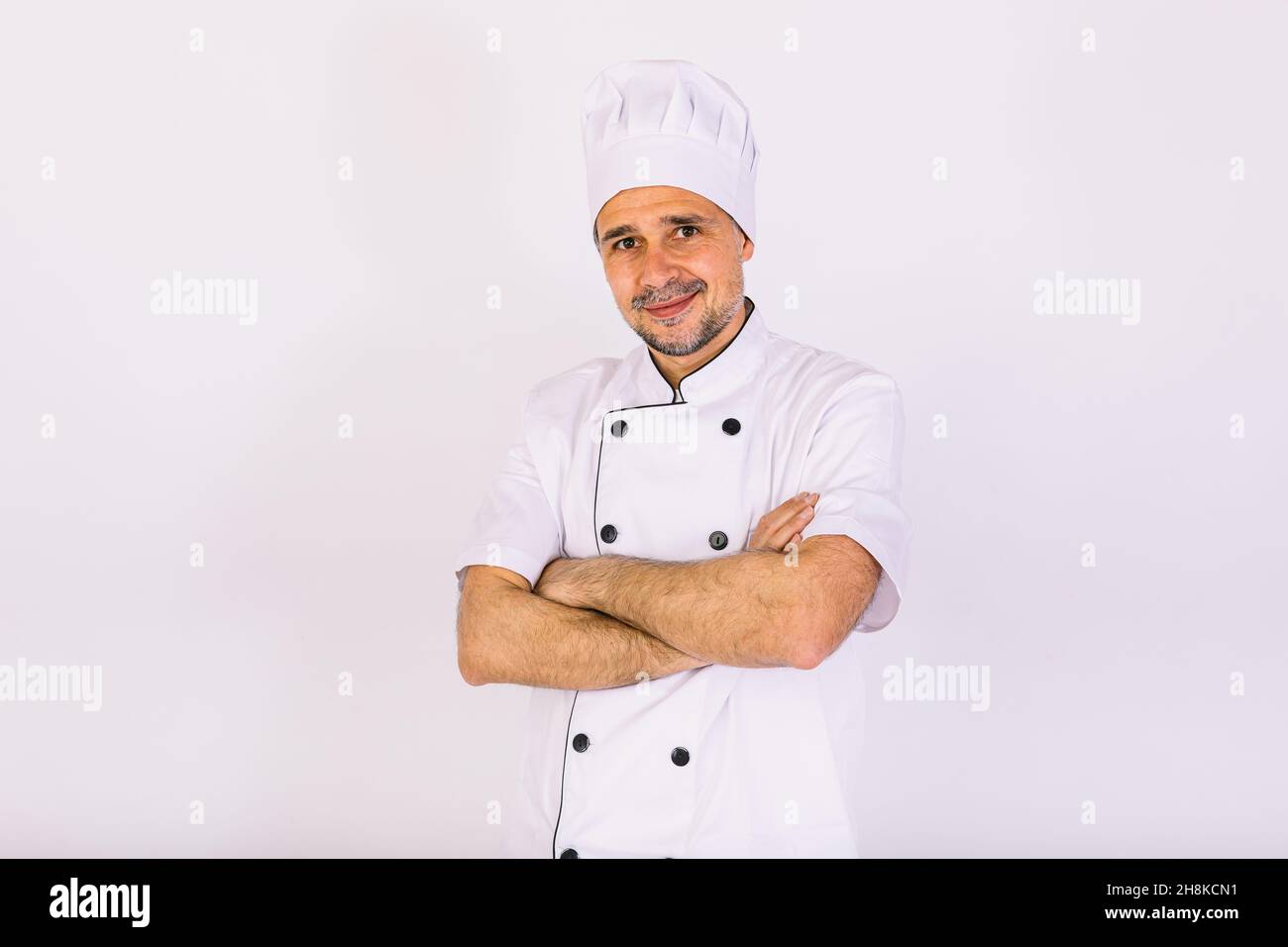 Chef cook wearing cooking jacket and hat, arms crossed, on white ...