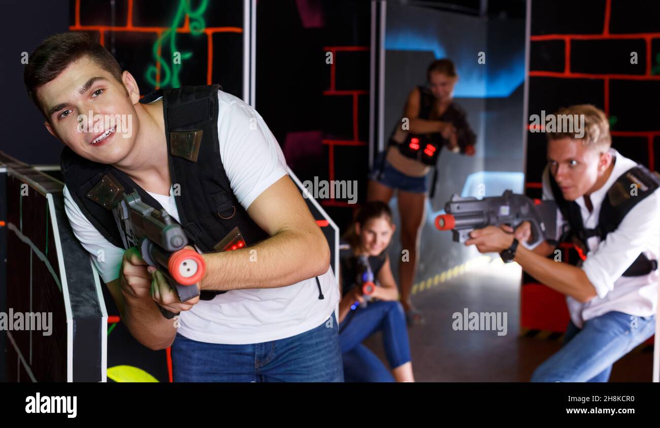 Guy with laser pistol and playing lasertag with his friends in dark ...