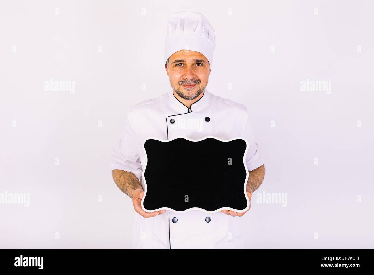 Chef cook wearing cooking jacket and hat, holding a blackboard, on ...